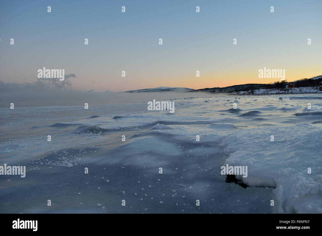 heavy sea ice fog in wintertime over frozen sea shore and colorful dawn ...