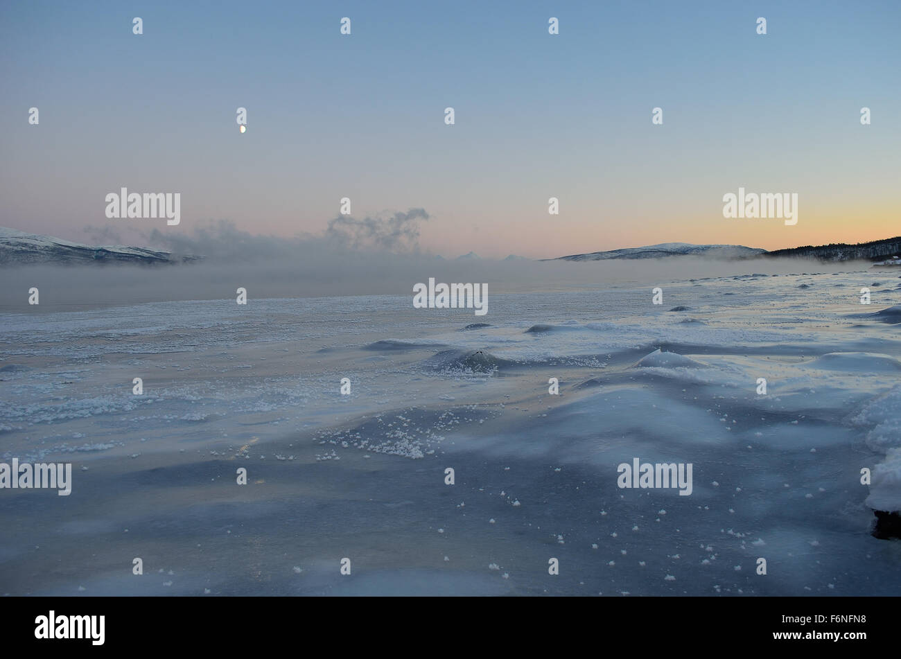 heavy sea ice fog in wintertime over frozen sea shore and colorful dawn ...
