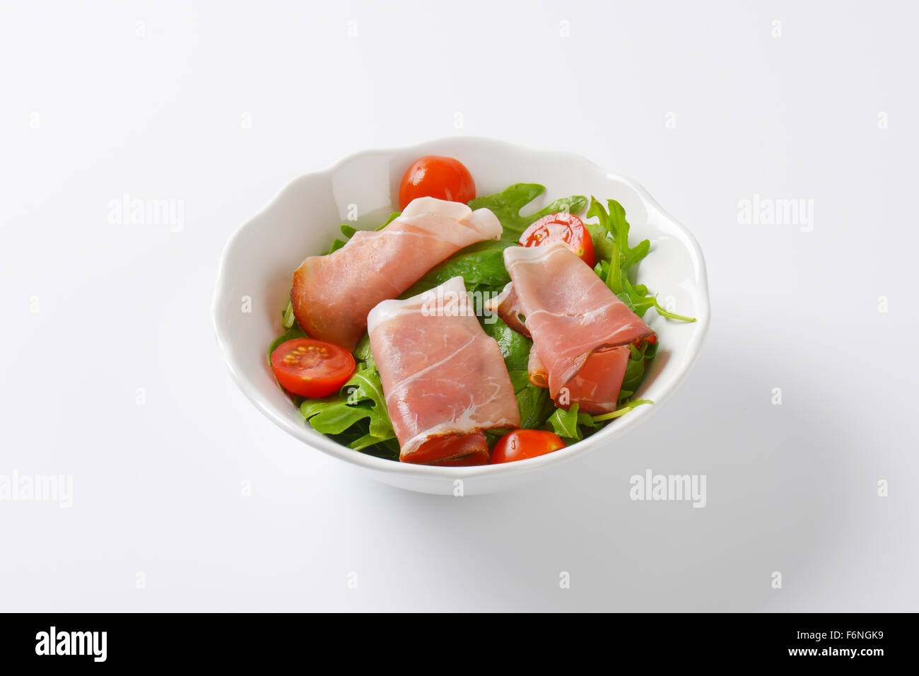 bowl of dried pork ham, rucola and spinach leaves and halved cherry ...