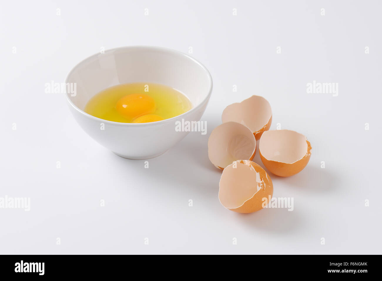 bowl of raw eggs and egg shells on white background Stock Photo - Alamy