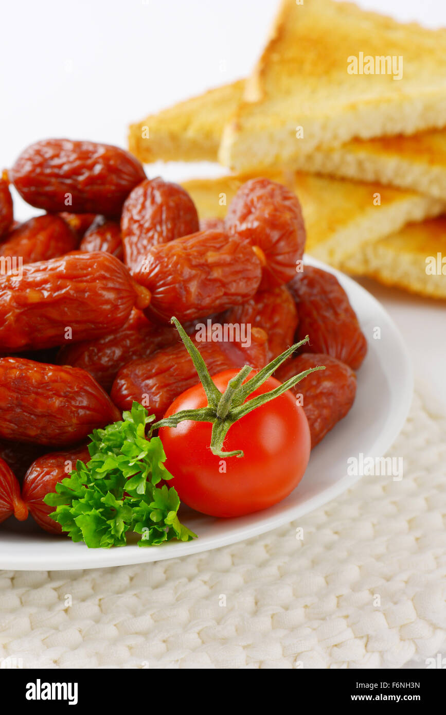 plate of mini sausages and crispy toasts on white table mat Stock Photo ...