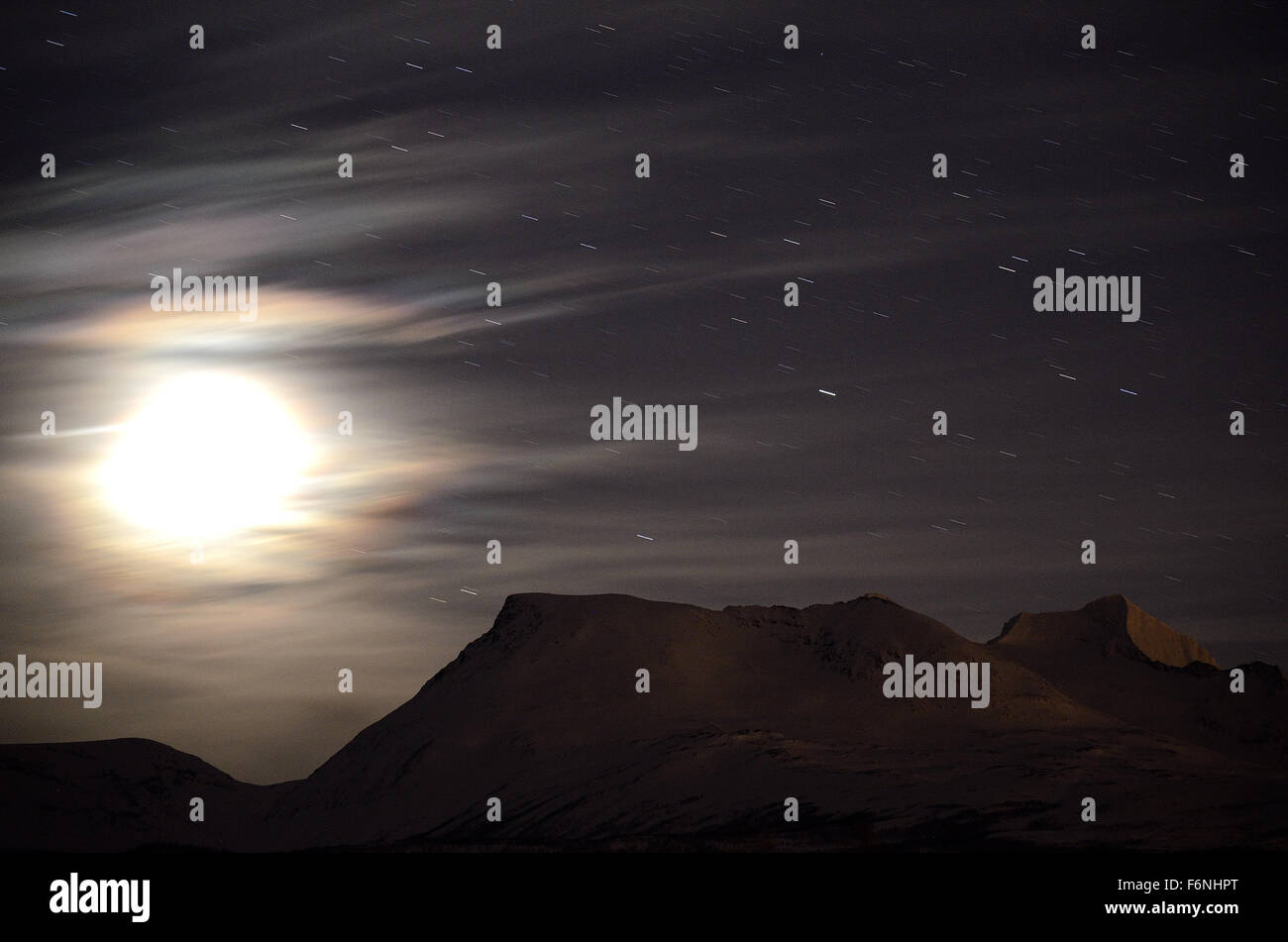 full moon on hazy winter night sky over snowy mountain peak Stock Photo ...