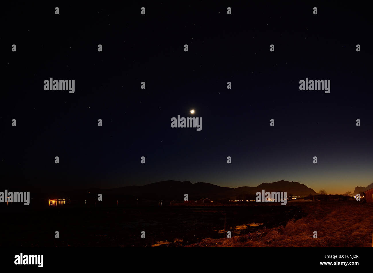 lights from settlement on a island at night time with mountain and ...