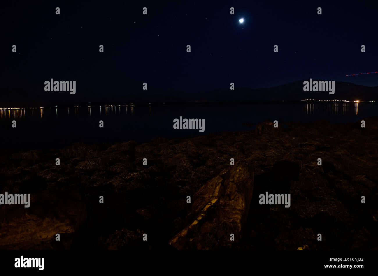 lights from settlement on a island at night time with mountain and ...