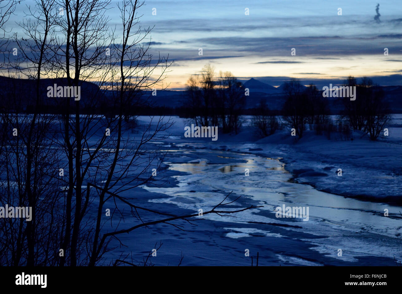 cold flowing river water with ice and snow on a blue winter dawn sky ...