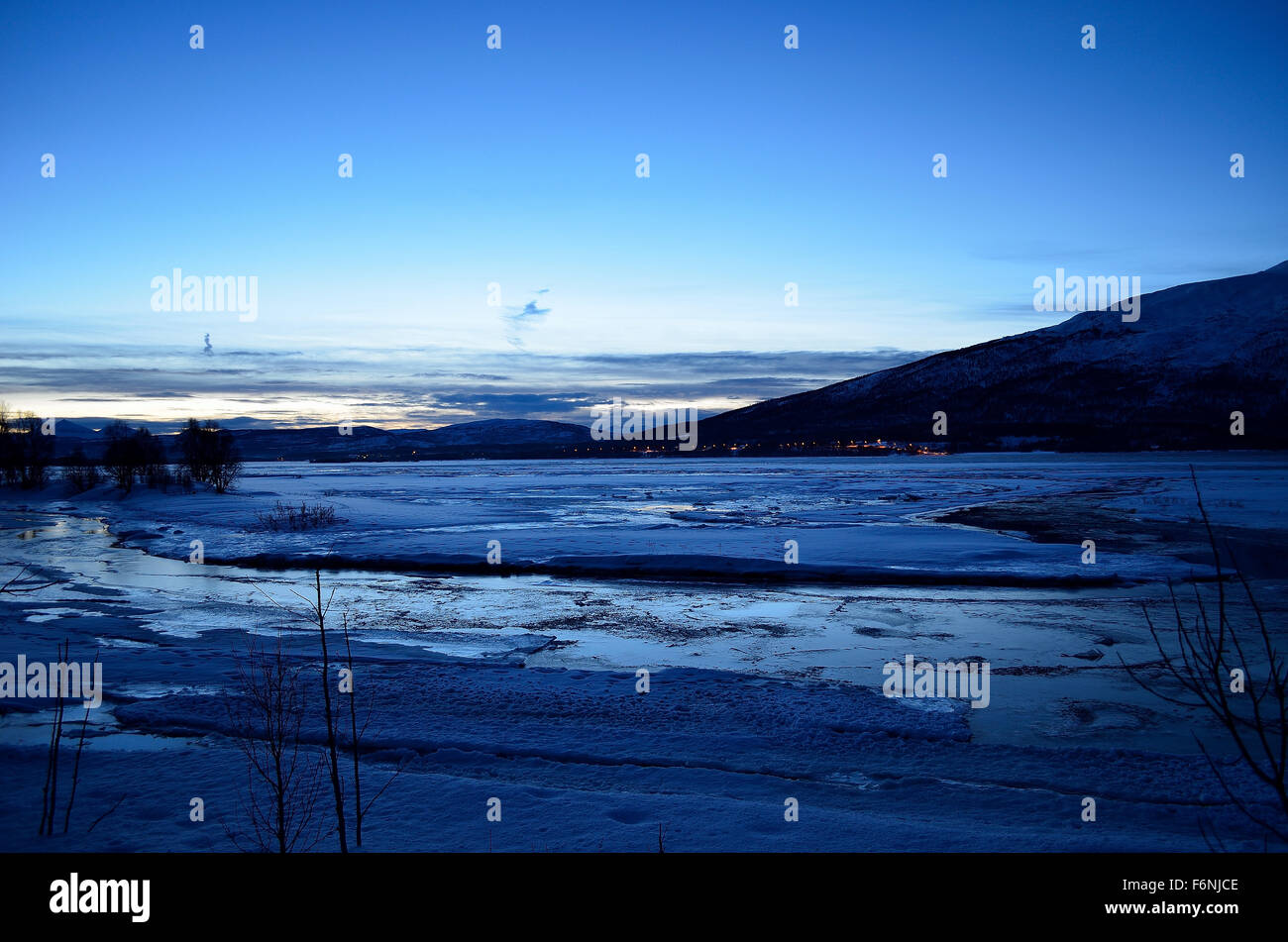cold flowing river water with ice and snow on a blue winter dawn sky ...
