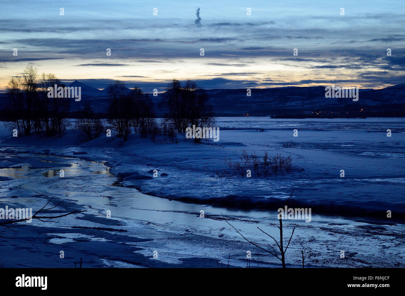 cold flowing river water with ice and snow on a blue winter dawn sky ...