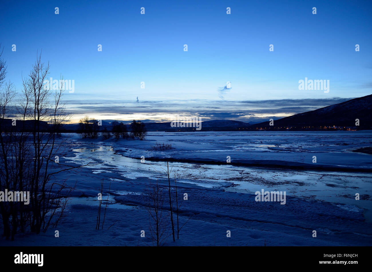 cold flowing river water with ice and snow on a blue winter dawn sky ...