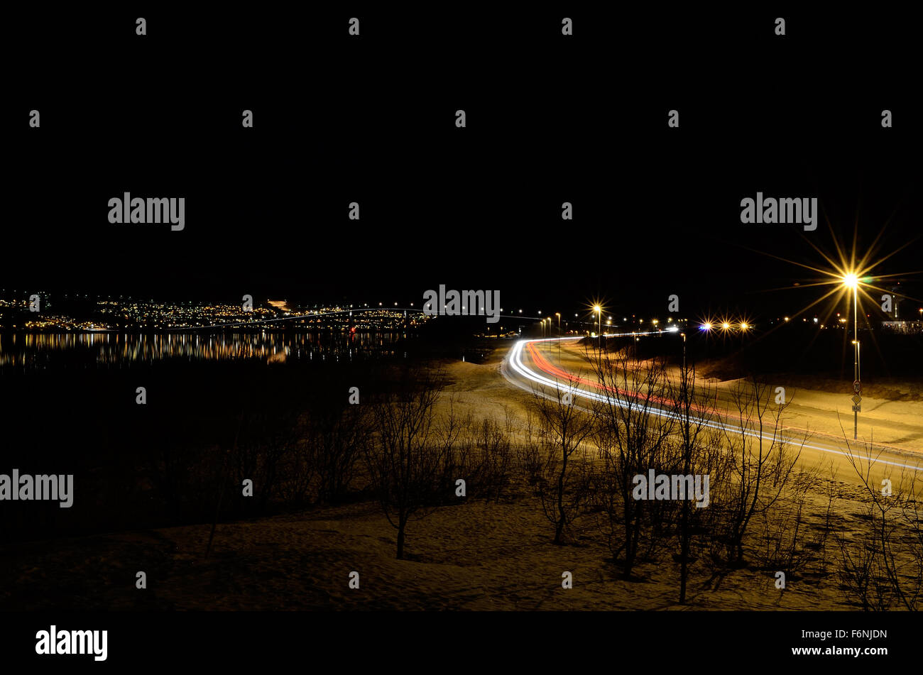 car traffic on winter road with illuminated bridge in the background ...