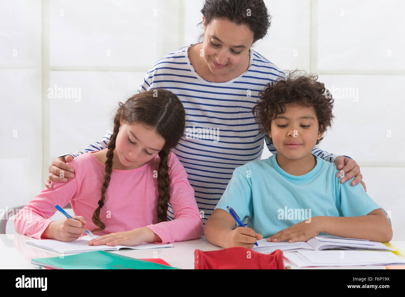Woman helping kids with homework Stock Photo - Alamy