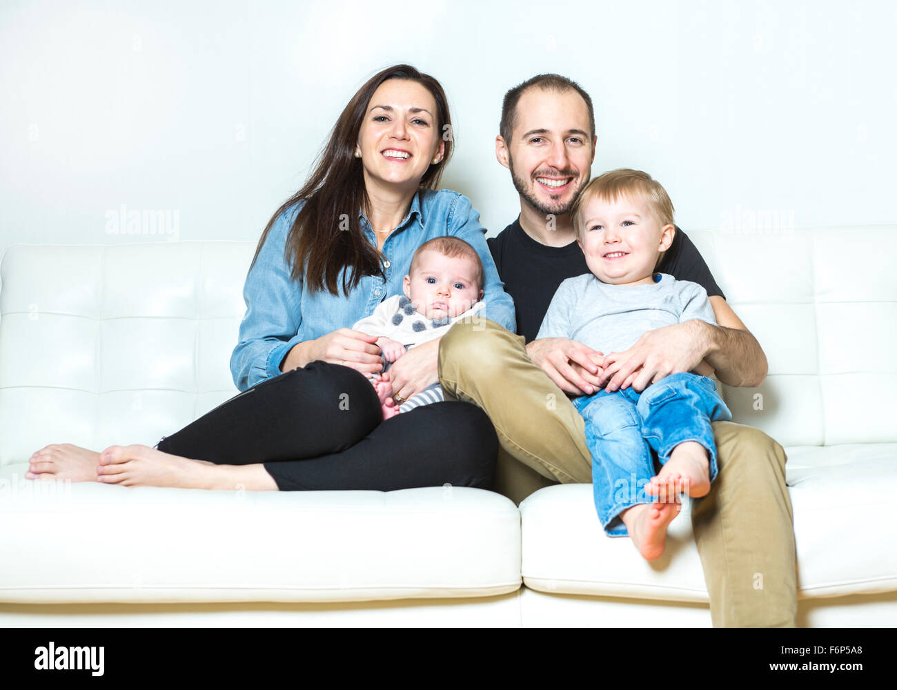 Young happy family with two children at home Stock Photo - Alamy