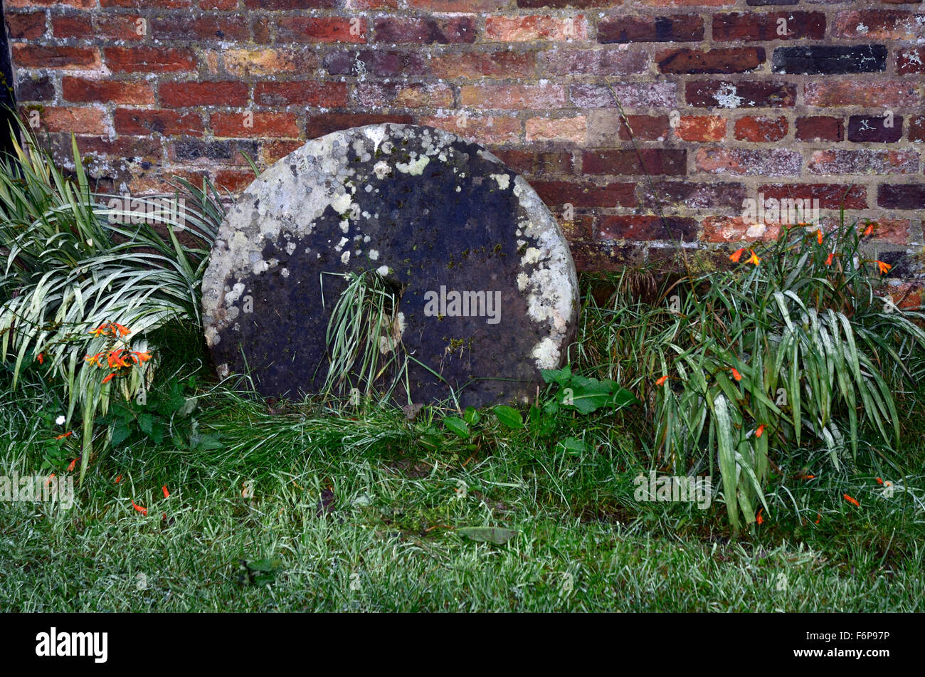 Old millstone leaning against a brick wall at Cheddleton Flint Mill ...