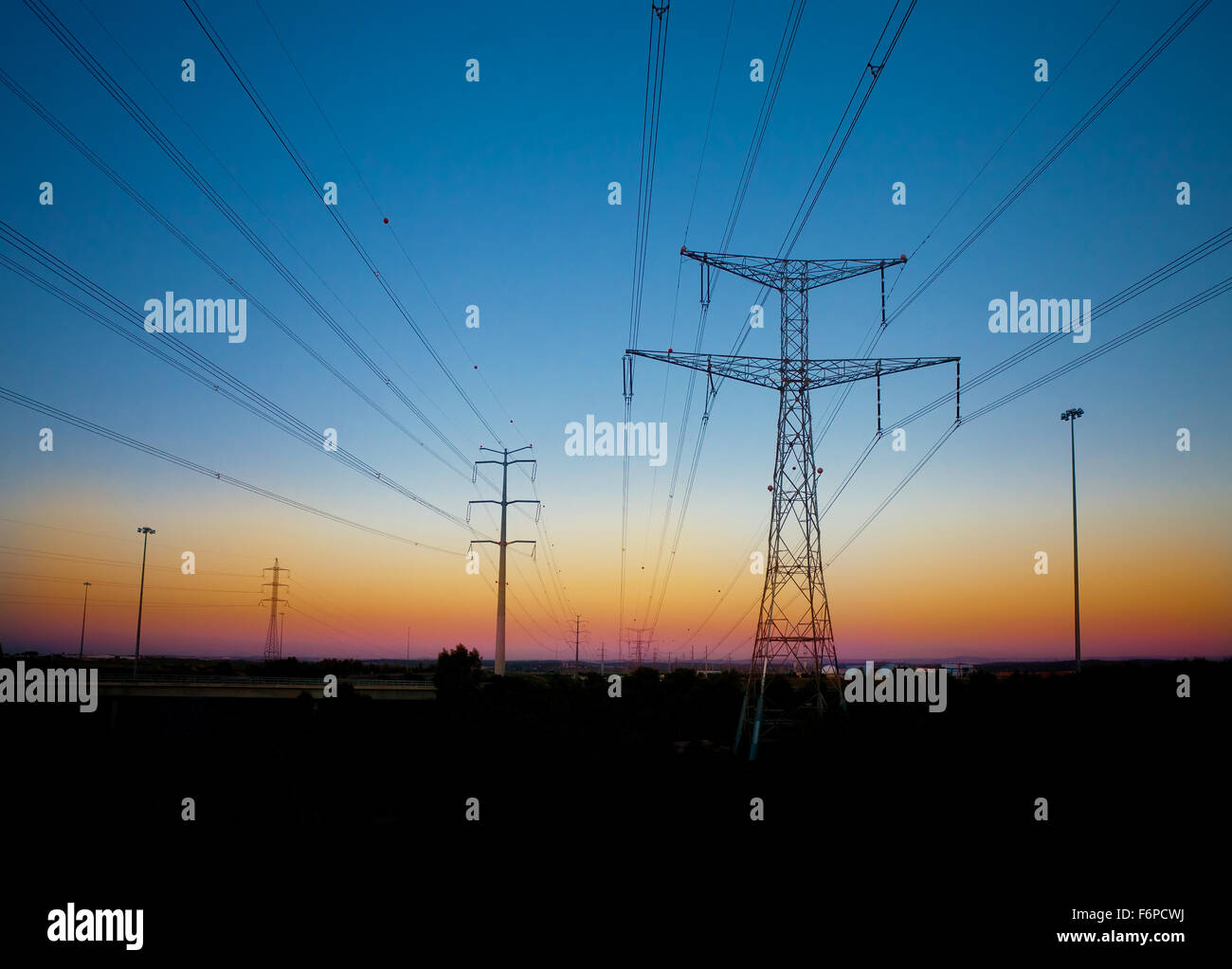 Amazing colors of sunset over dark electric power transmission line ...