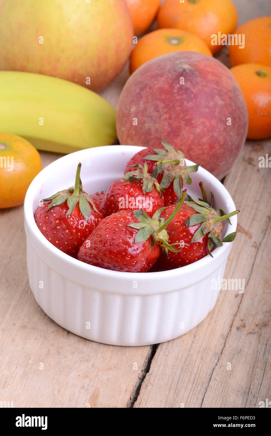 Bananas apple mandarin peach strawberry on wooden background as health ...