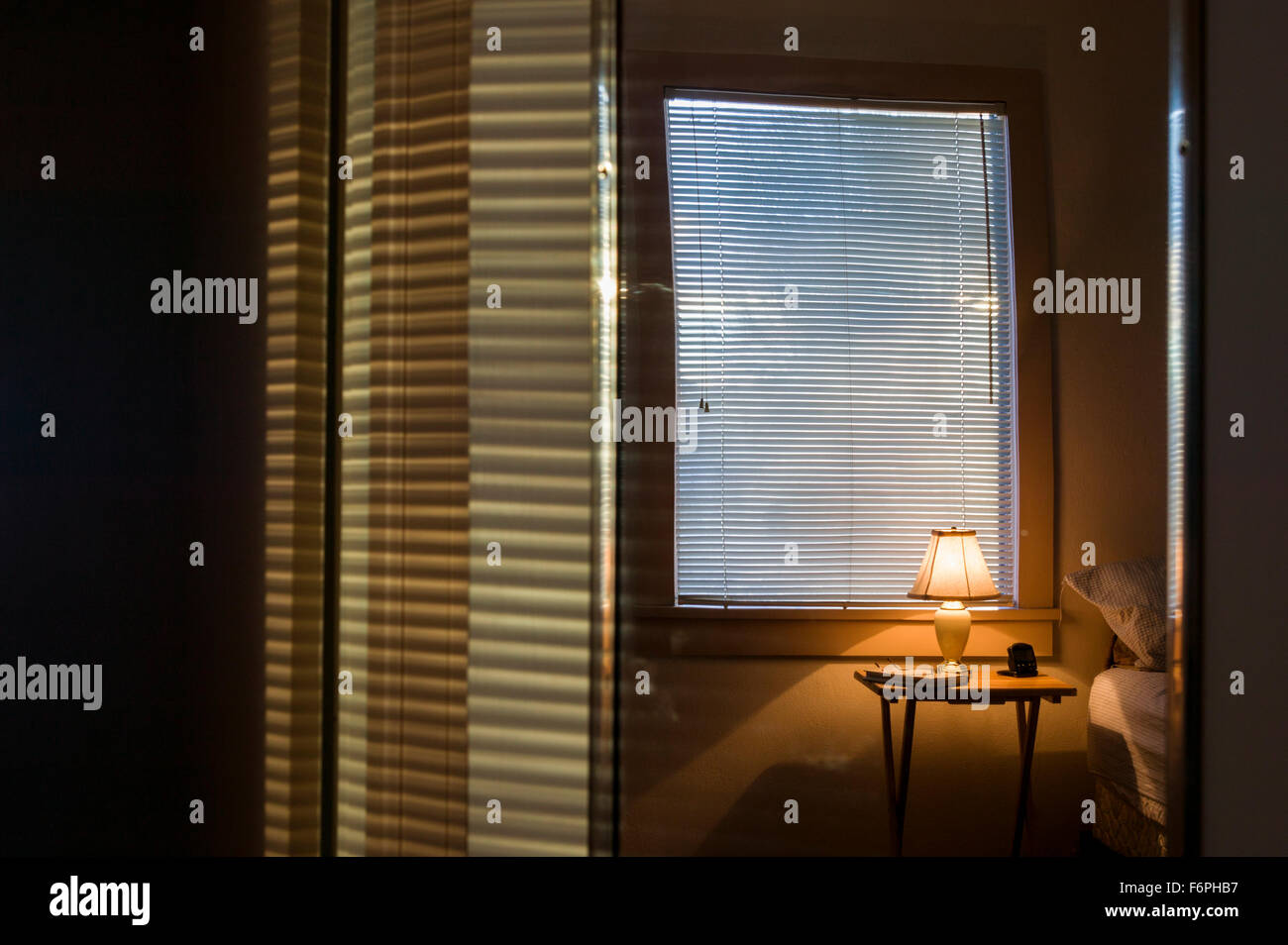 Still life of table, lamp, window and patterns cast by Venetian Blind ...