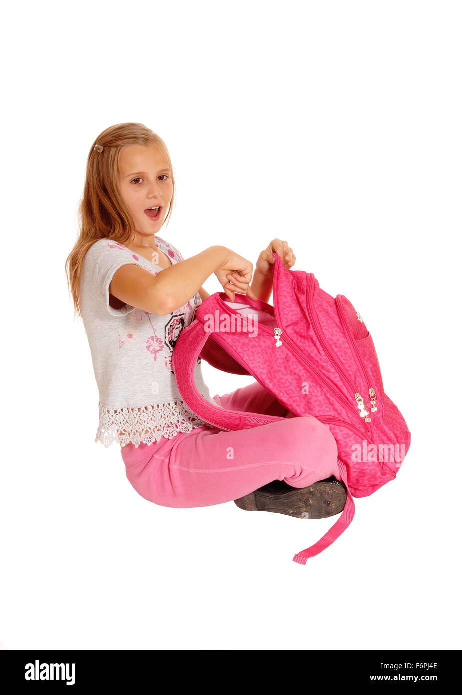 A beautiful young girl opening her pink backpack, pointing into it and ...