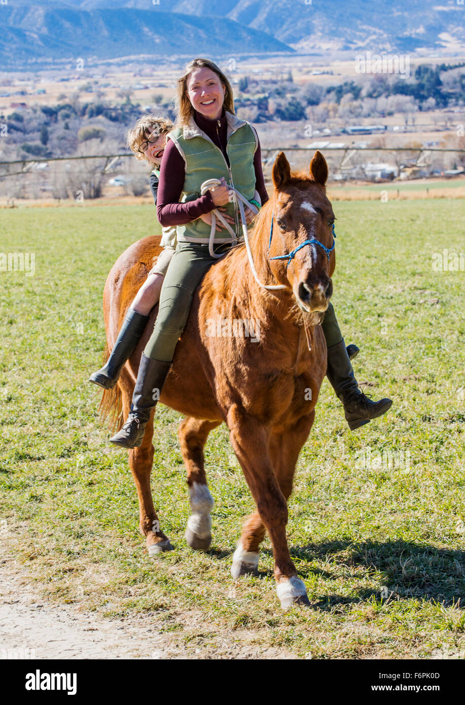 Attractive mother and young son riding horse in ranch pasture Stock ...