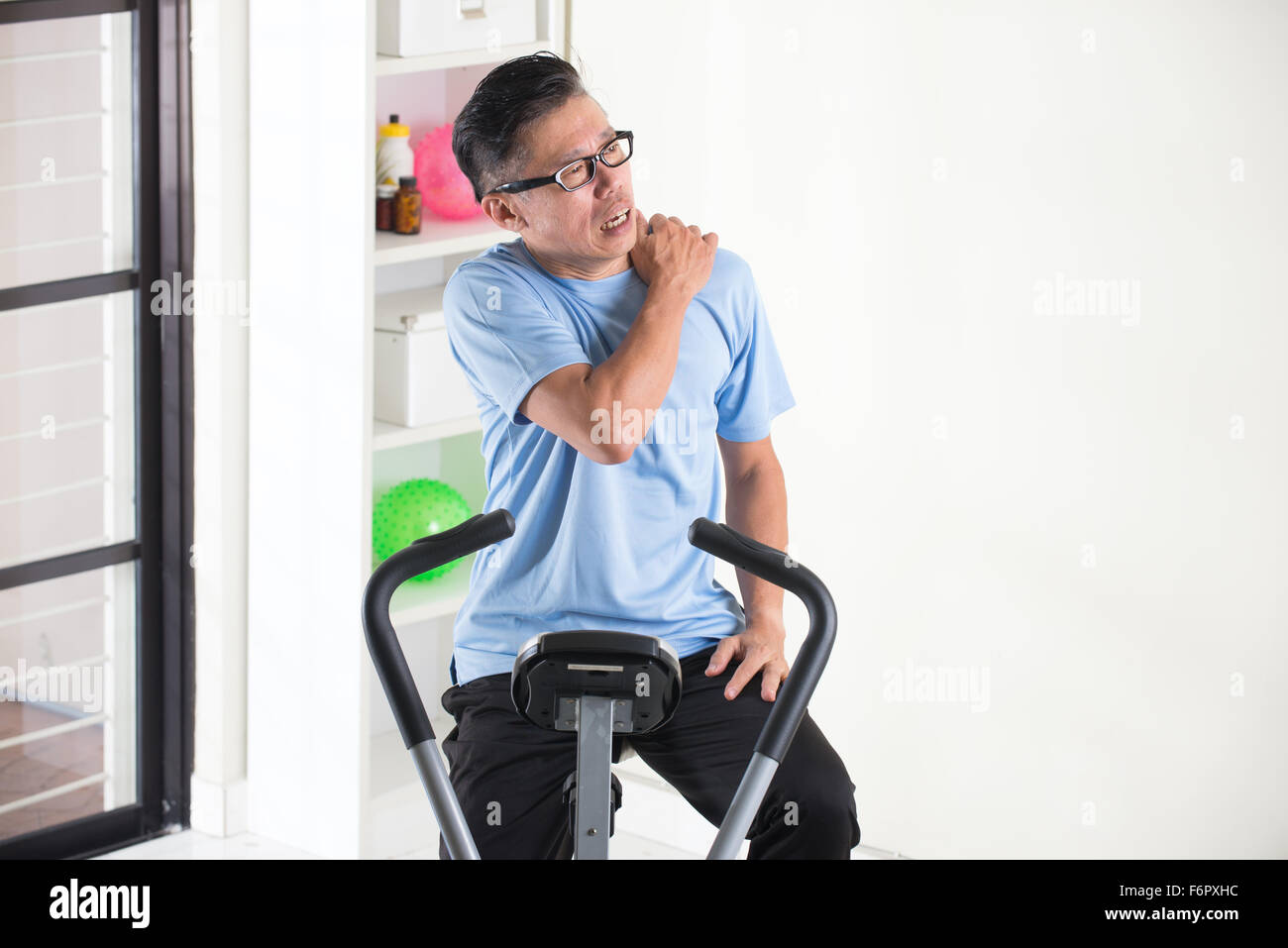 asian senior male shoulder injury on exercise bike Stock Photo - Alamy