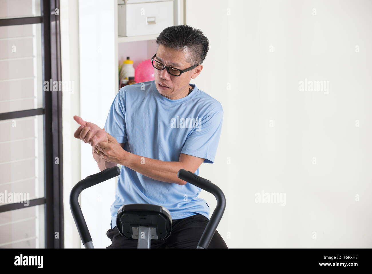 asian senior male hand injury on exercise bike Stock Photo - Alamy