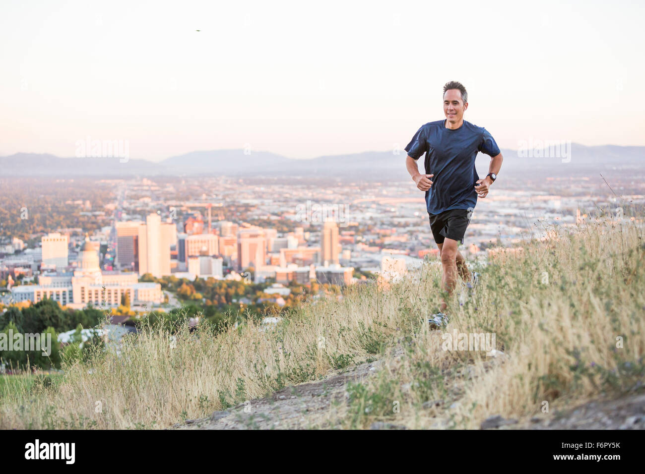 Mixed race man running on hilltop over Salt Lake City, Utah, United ...
