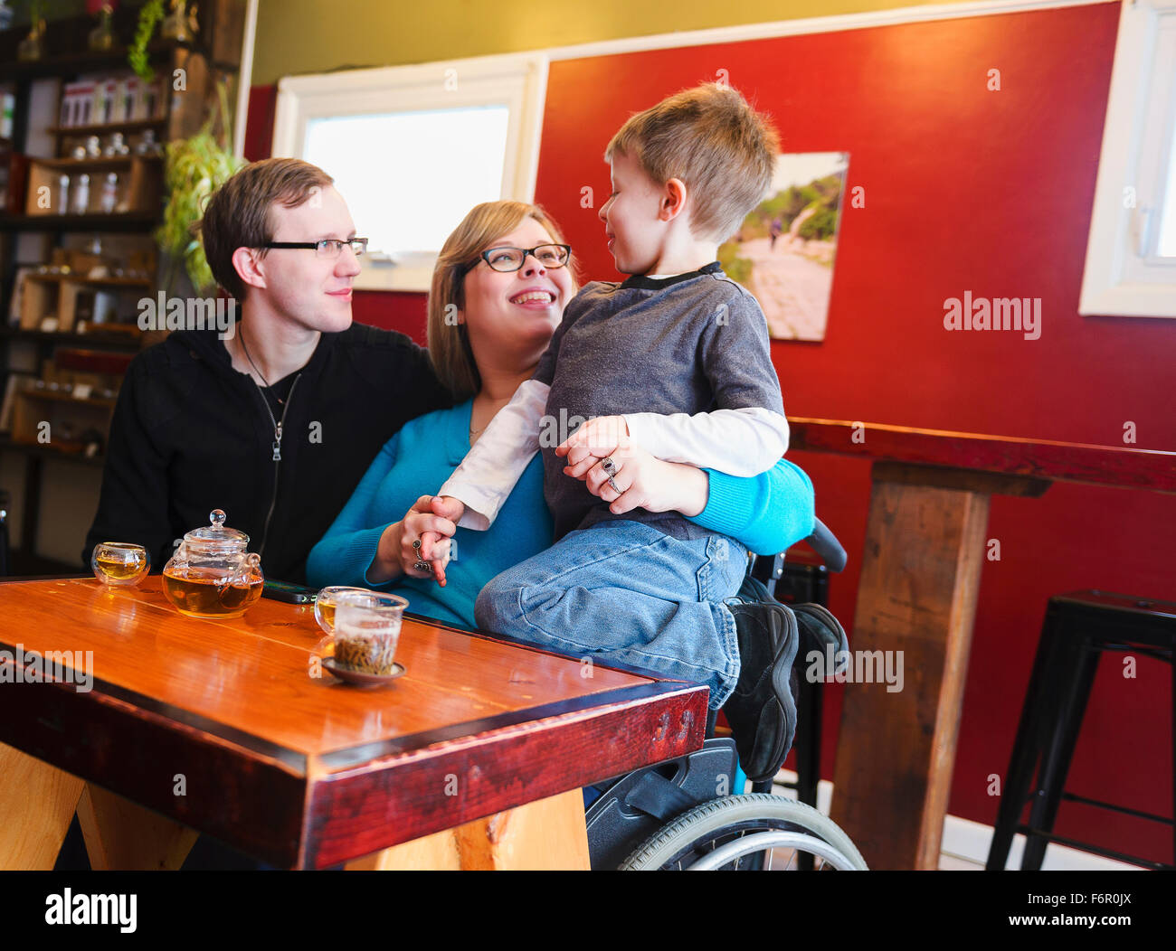 Paraplegic mother holding son in tea shop Stock Photo - Alamy