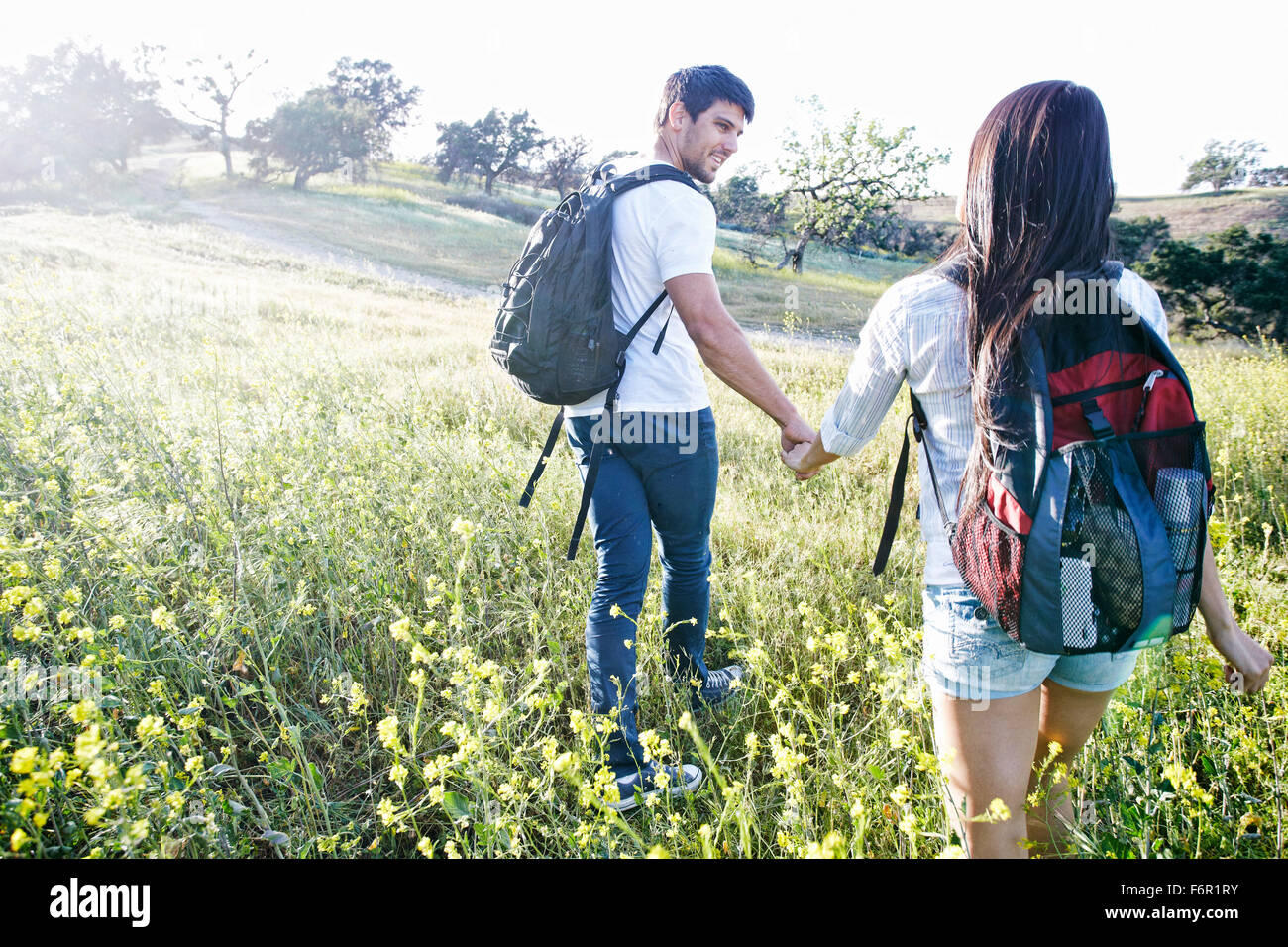Couple carrying backpacks in field Stock Photo - Alamy