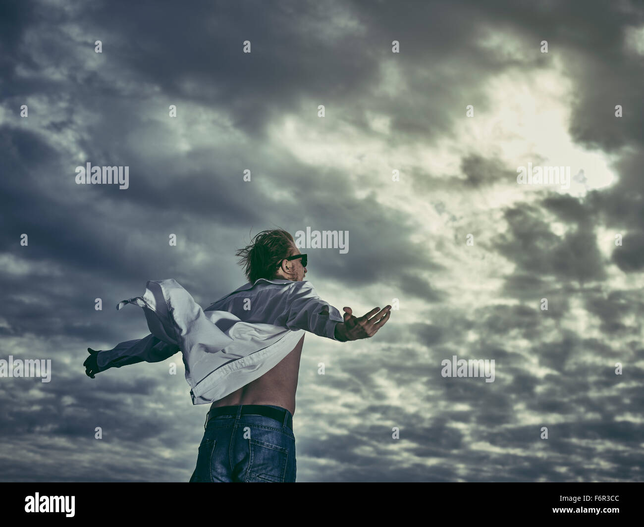 Handsome man wearing white shirt and jeans, he spread her arms and ...