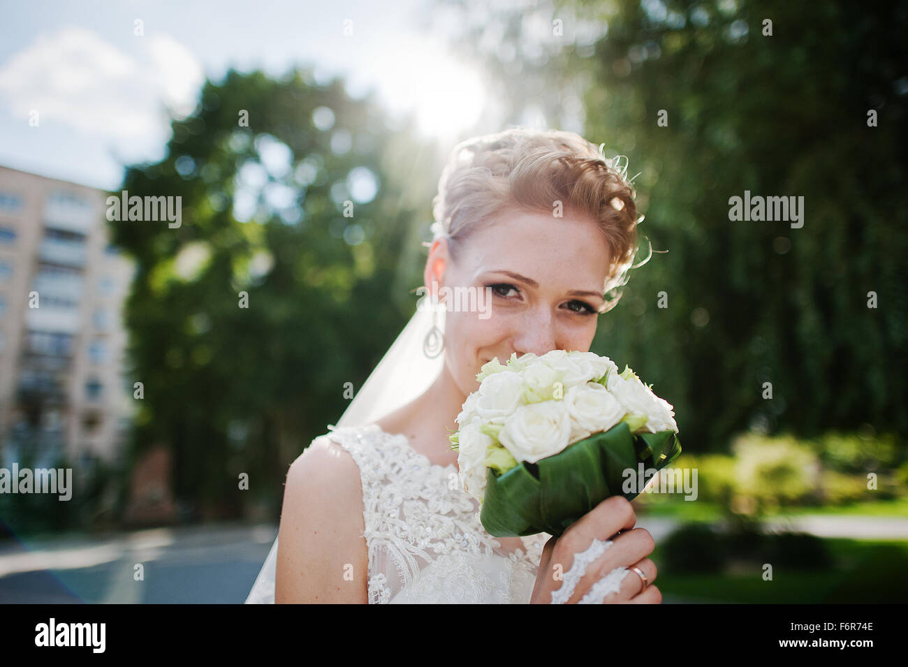 Blonde bride sniffing wedding bouquet Stock Photo - Alamy