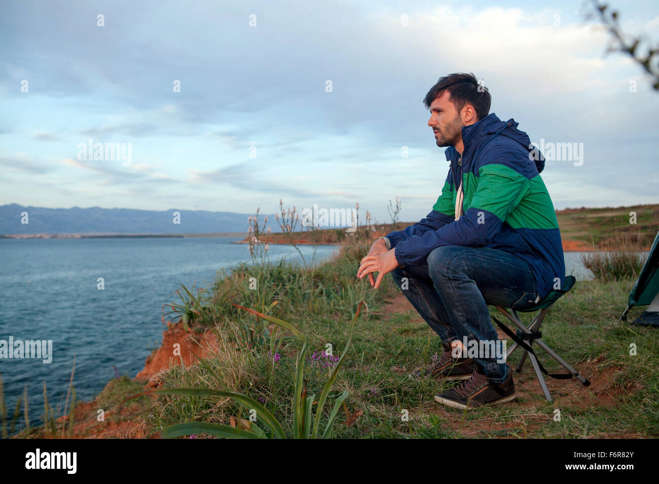Young man sitting by cliff edge hi-res stock photography and images - Alamy