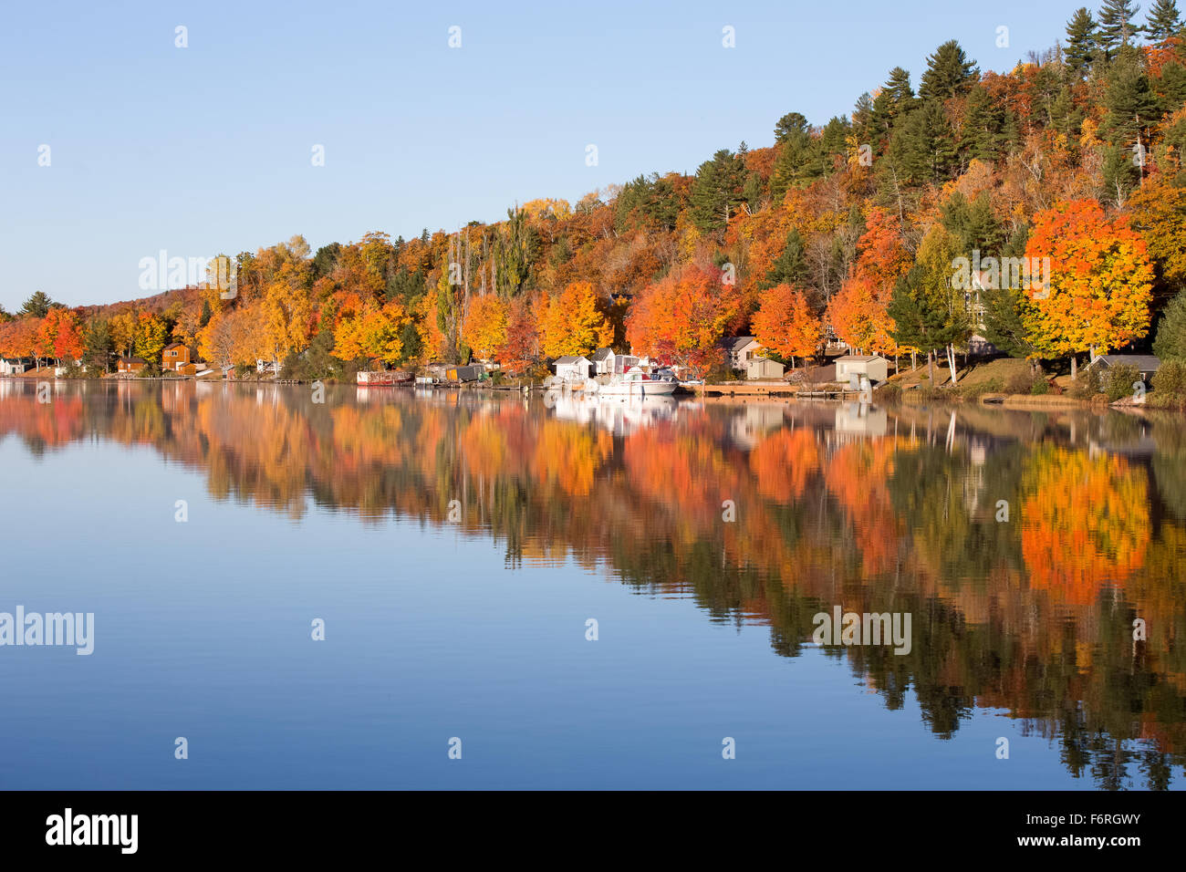 Brilliant fall colors reflected in a smooth, calm lake. Photographed in ...