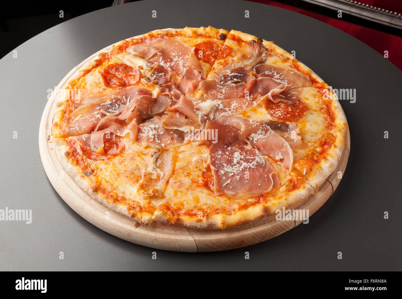 pizza with ham and sausage on wooden plate Stock Photo - Alamy