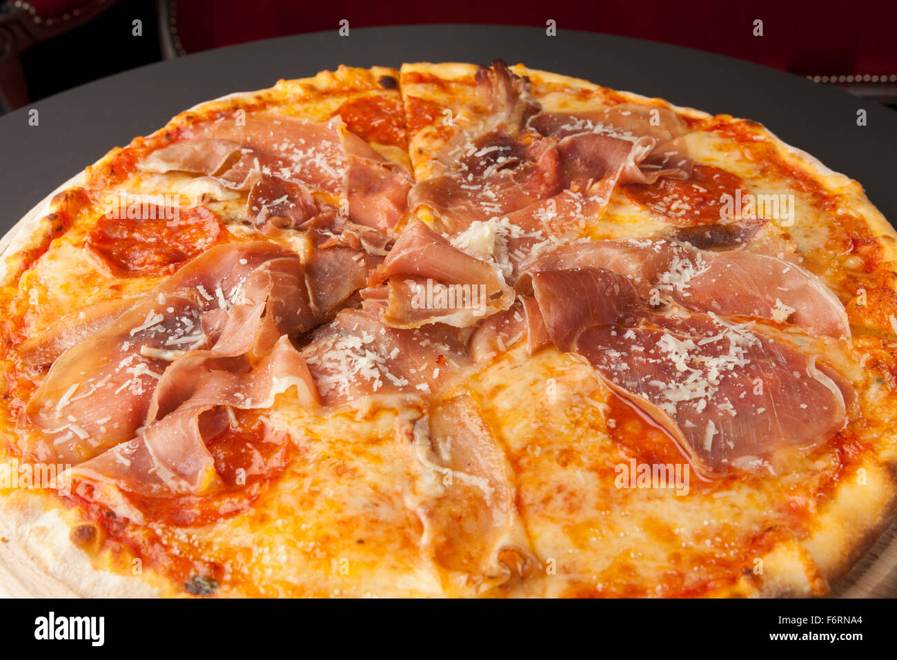 pizza with ham and sausage on wooden plate Stock Photo - Alamy