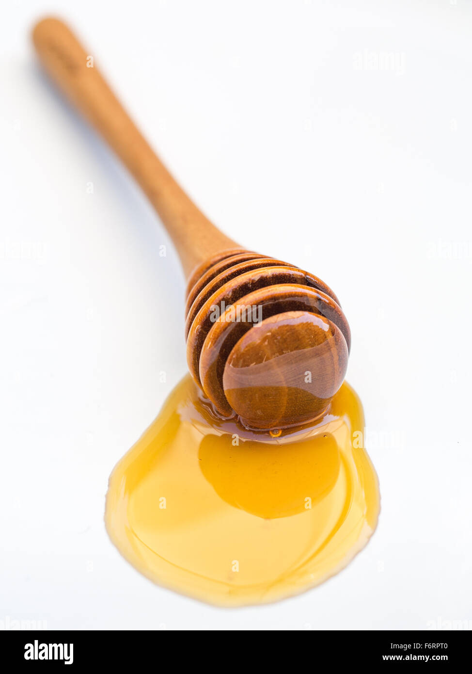 Honey dipper with pool of honey on white plate Stock Photo - Alamy