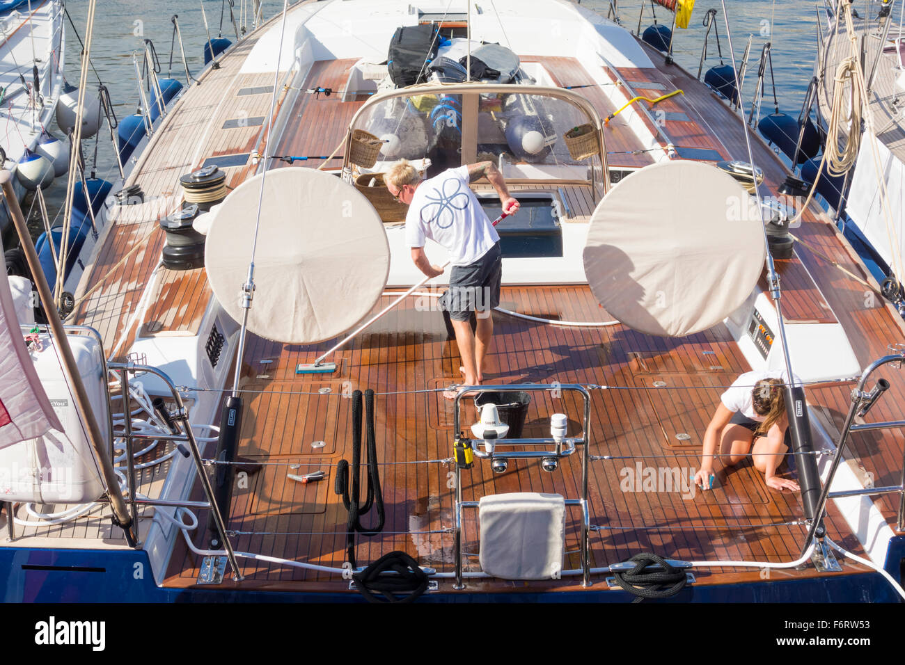 Young male and female crew members scrubbing deck of luxury yacht Stock ...