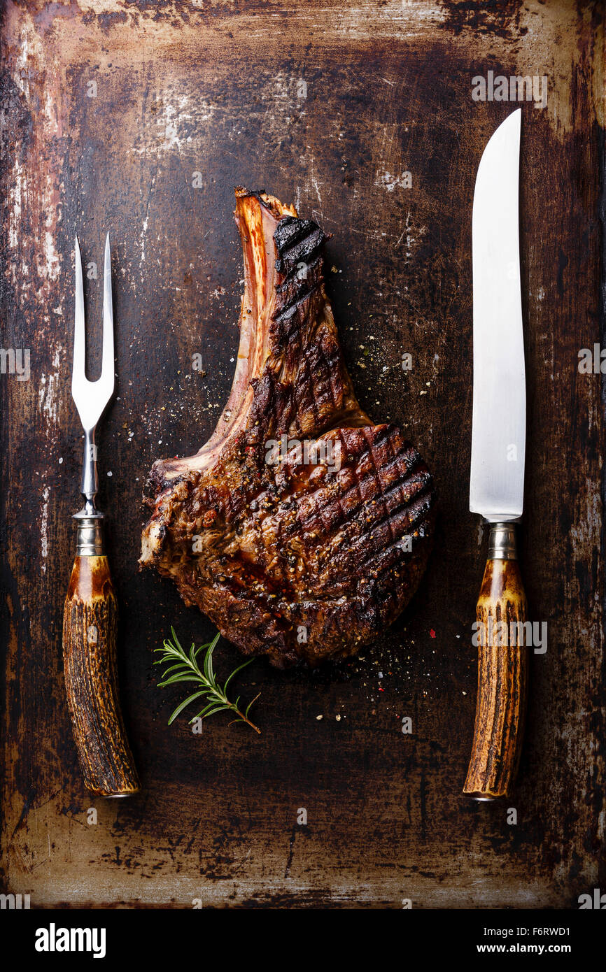 Grilled Ribeye Steak on bone and fork and knife carving set on old ...