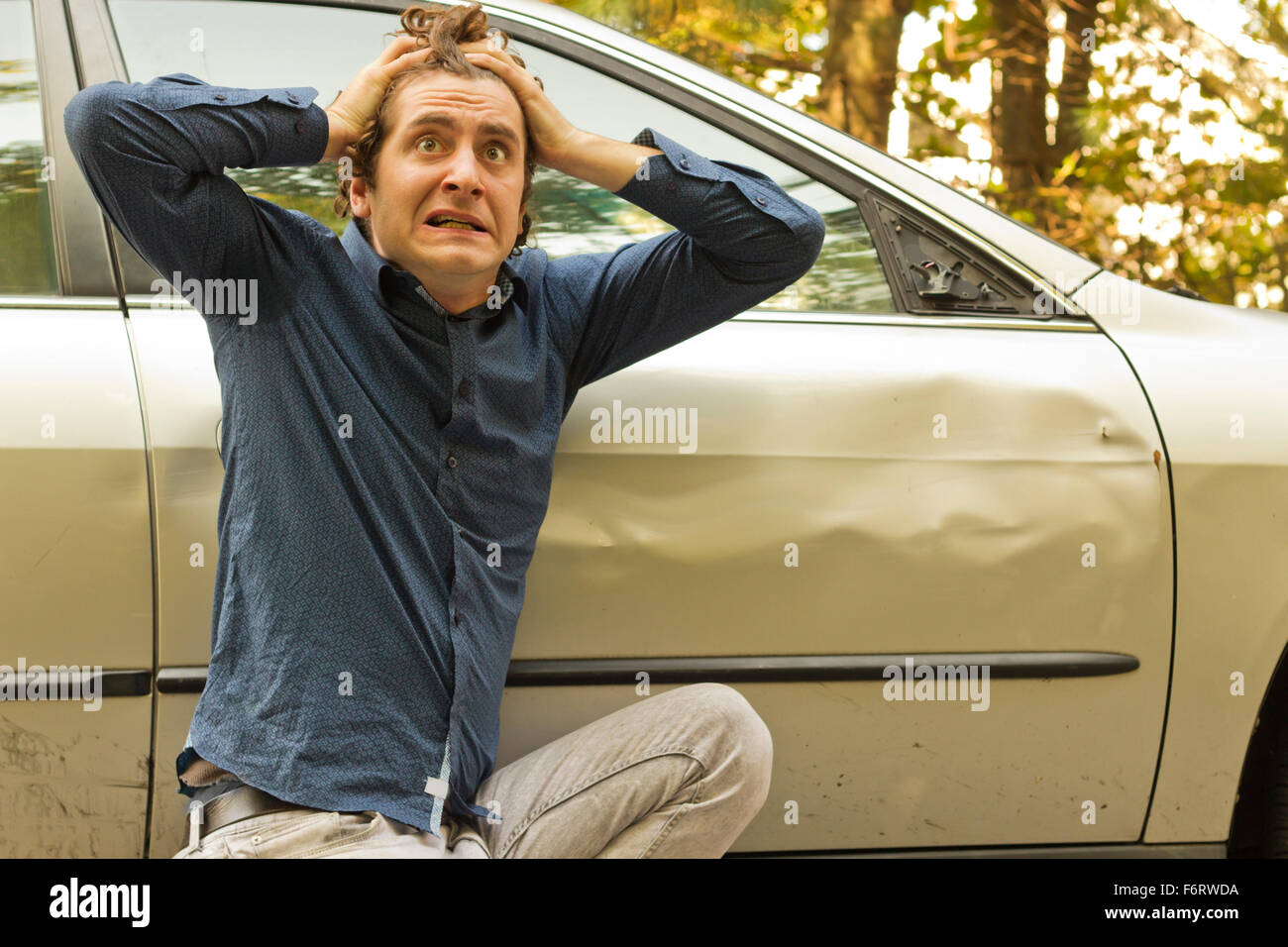 Silly man makes angry annoyed facial expression about dame to his car ...