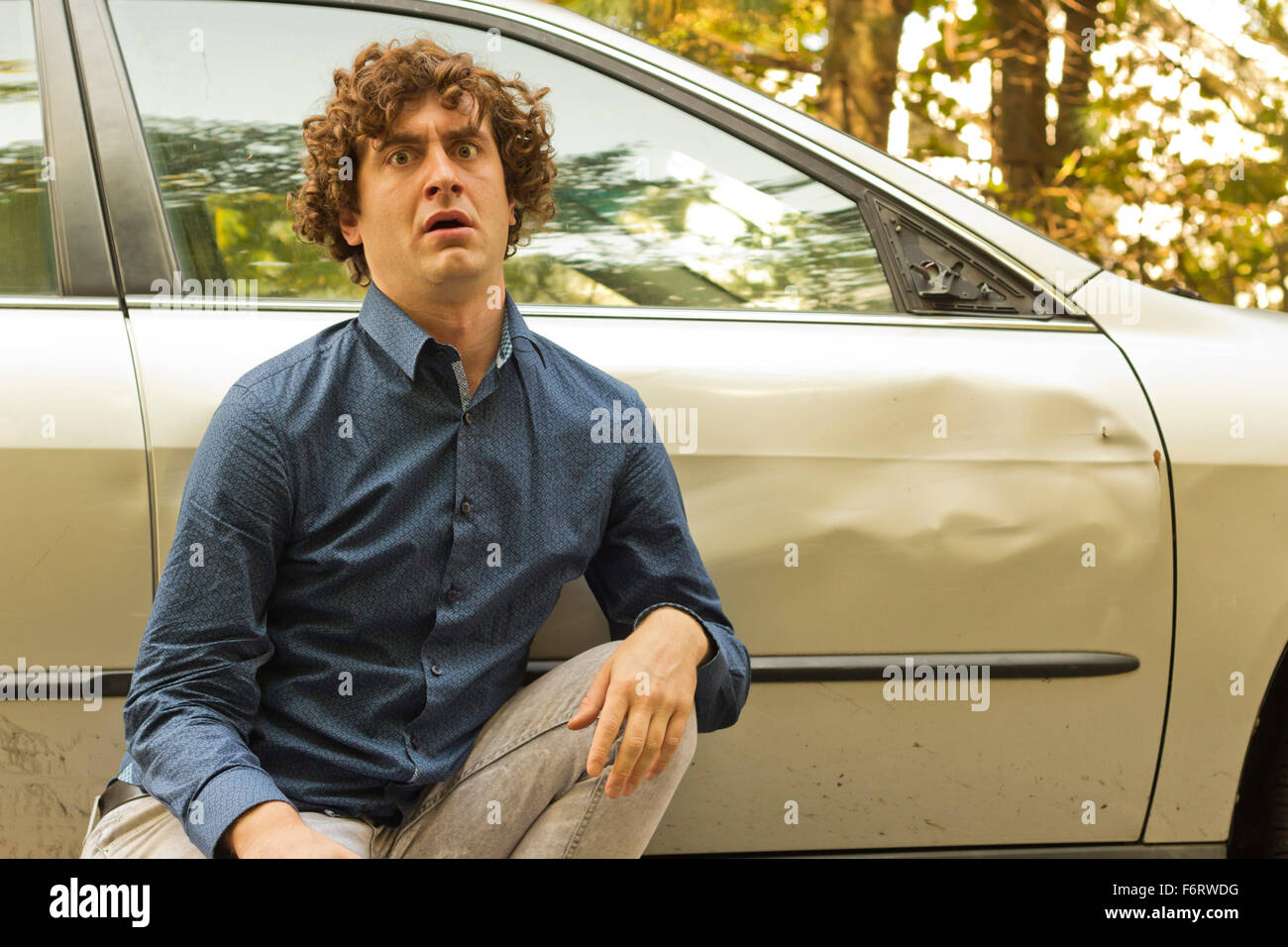 Silly man makes angry annoyed facial expression about dame to his car ...