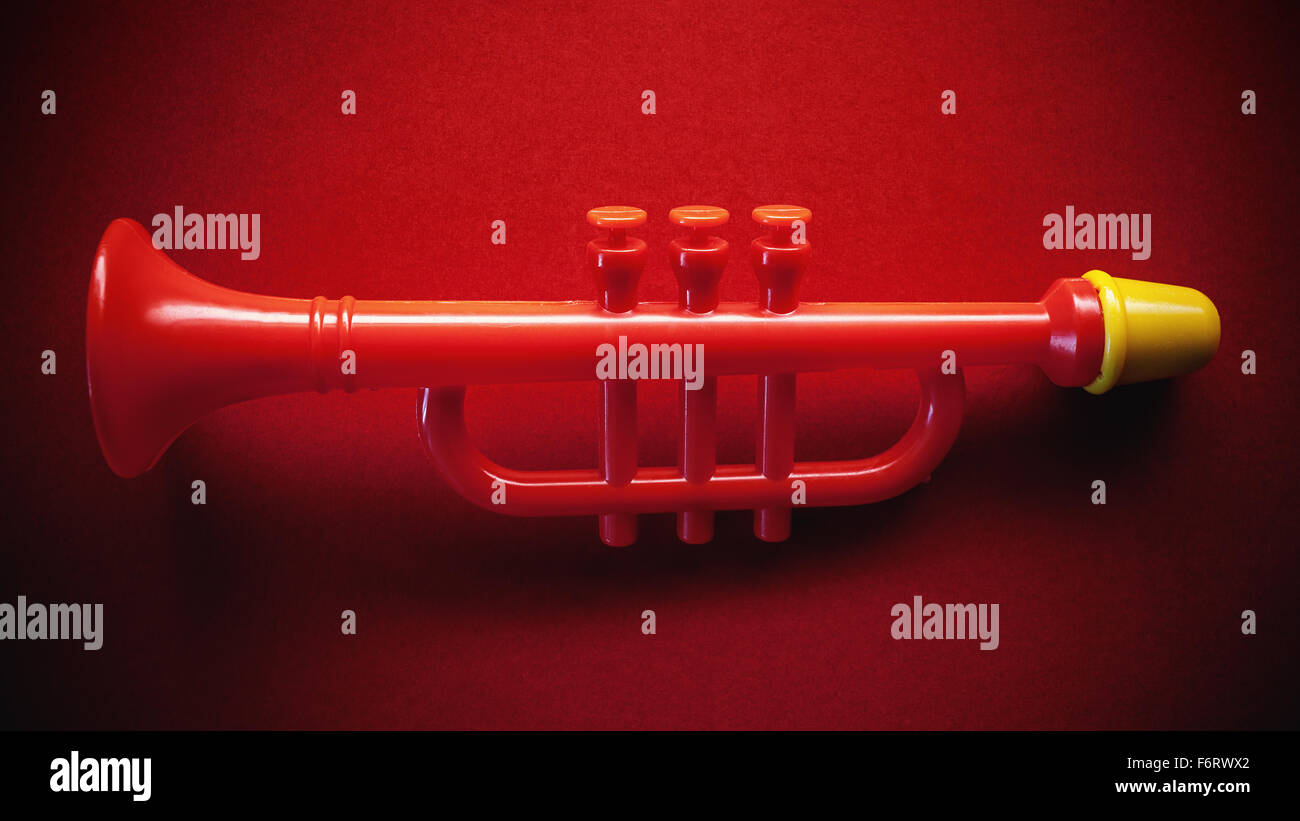 Small red trumpet as a toy, on red background Stock Photo - Alamy