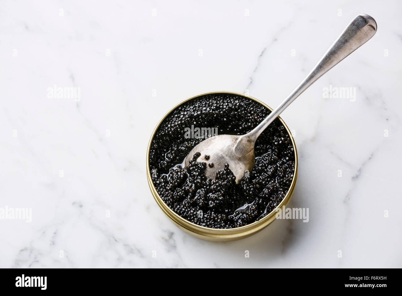 Sturgeon black caviar in can and spoon on white marble background Stock ...