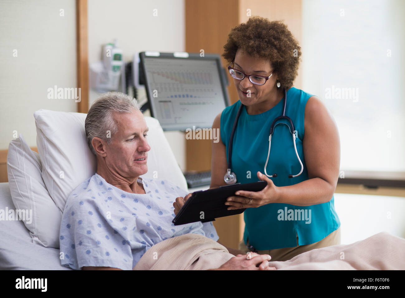 Doctor using digital tablet with patient in hotel room Stock Photo - Alamy