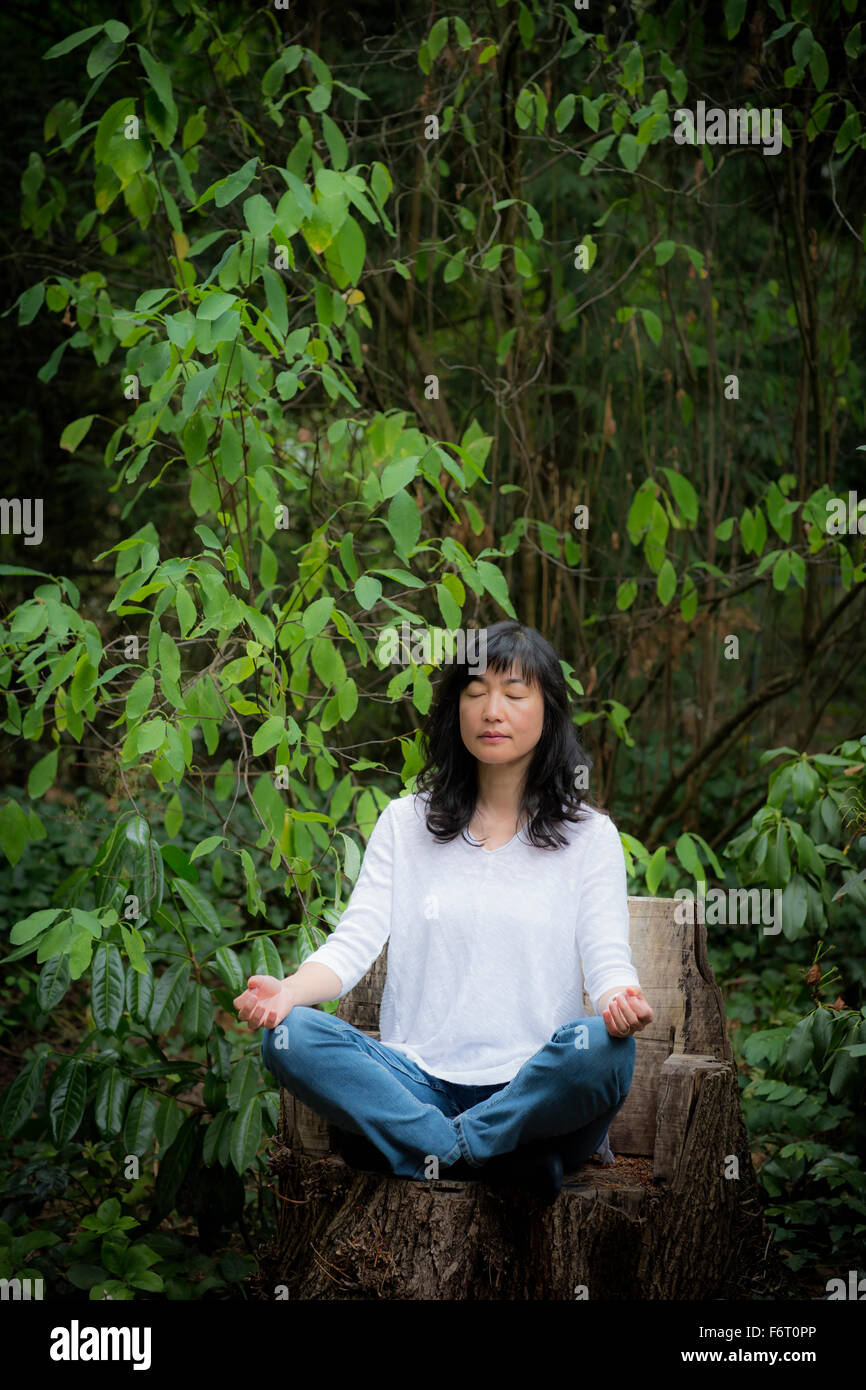 Japanese woman meditating in garden Stock Photo - Alamy