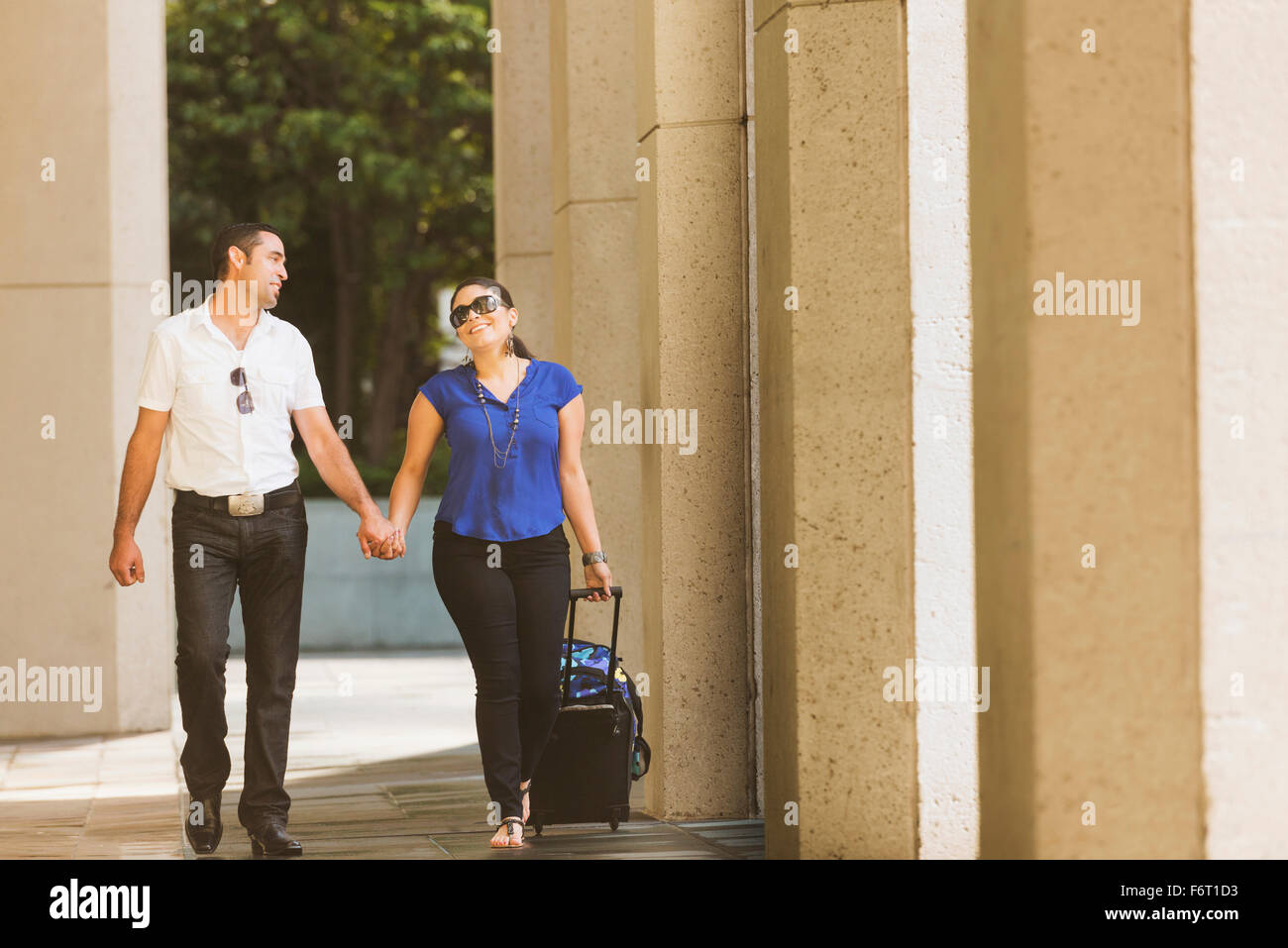Hispanic couple holding hands under columns Stock Photo - Alamy