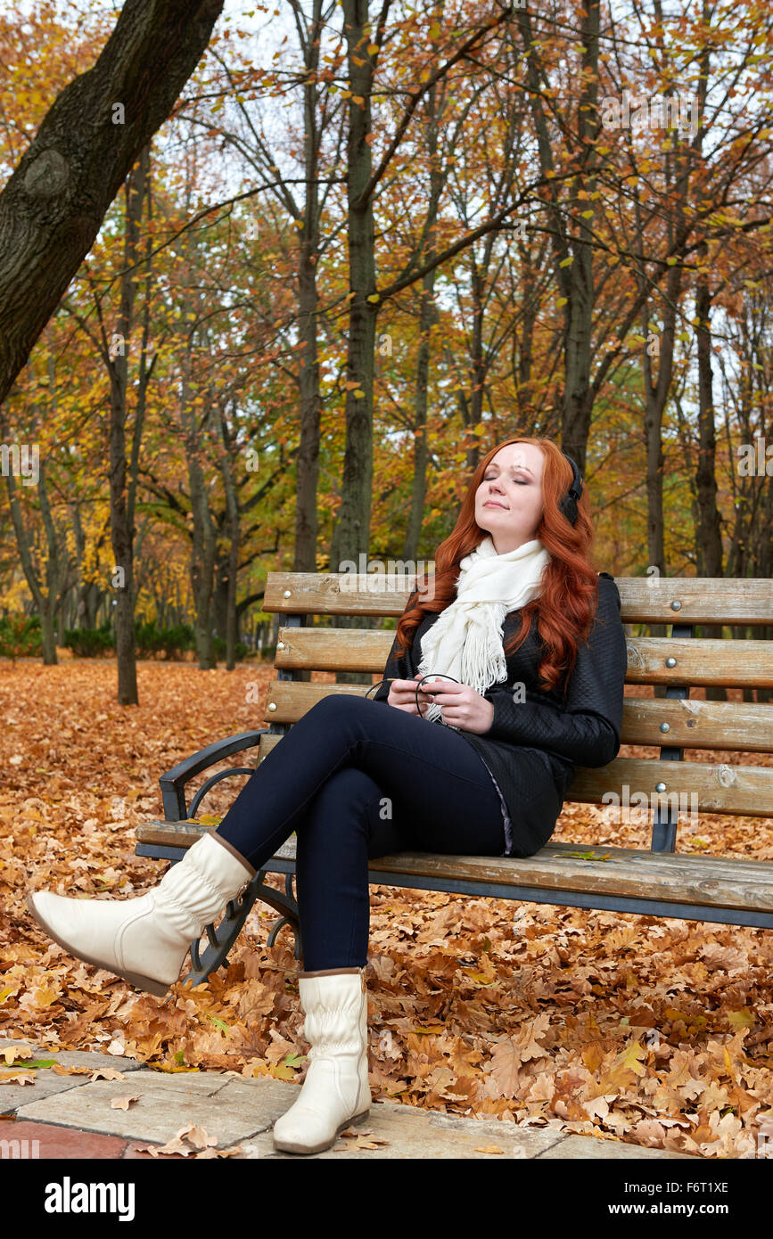 Redhead Girl Listen Music On Headphones In City Park Fall Season Stock