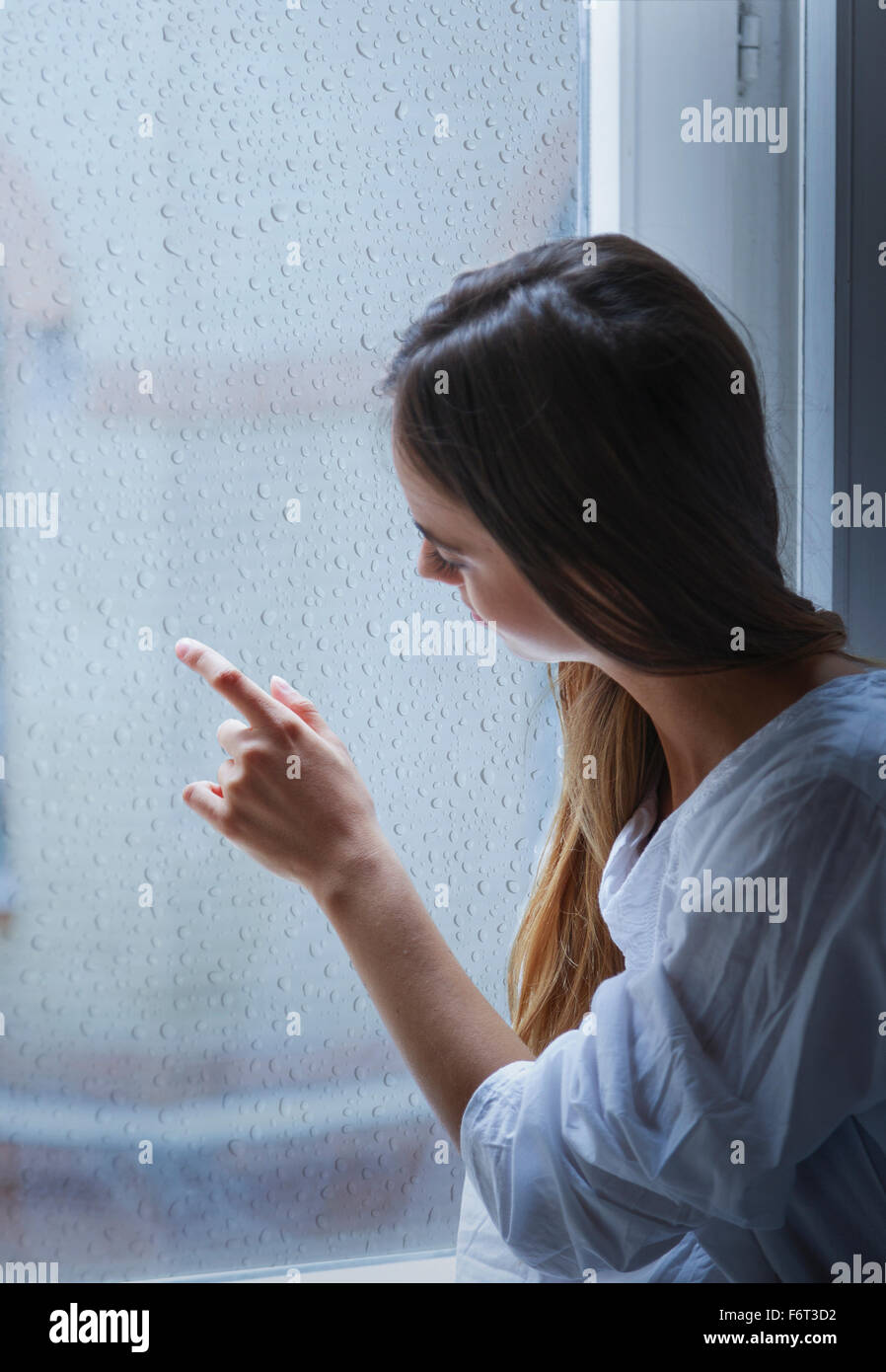Caucasian woman looking out window Stock Photo - Alamy