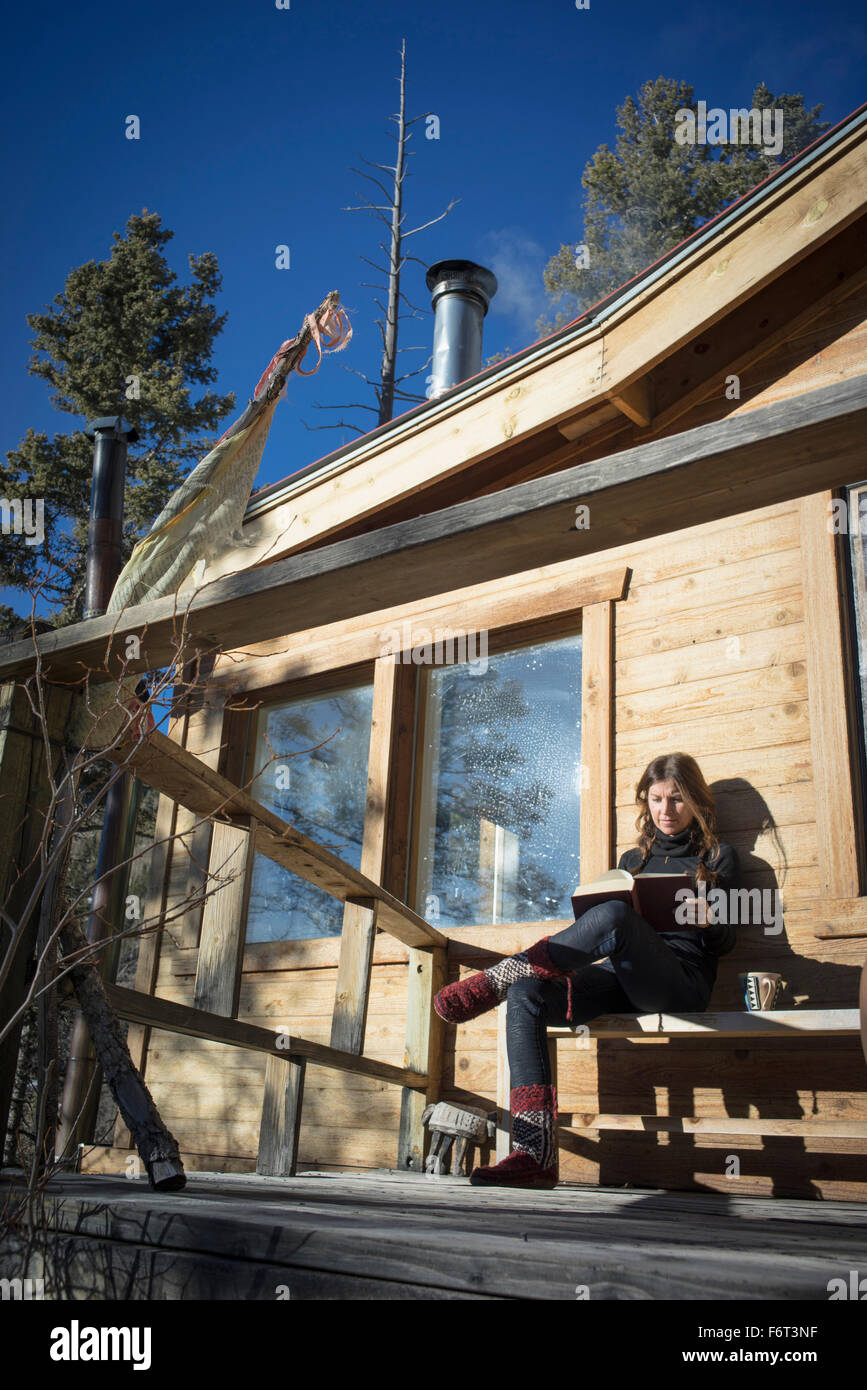 Caucasian woman reading book on cabin porch Stock Photo - Alamy