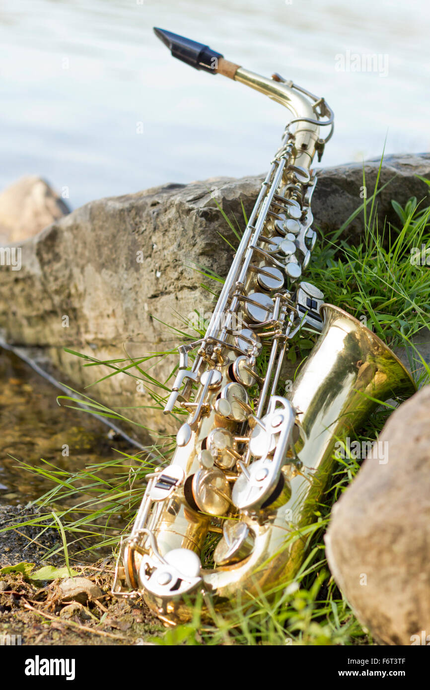 Summer Jazz saxophone in nature lying on rocks lakeside Stock Photo - Alamy