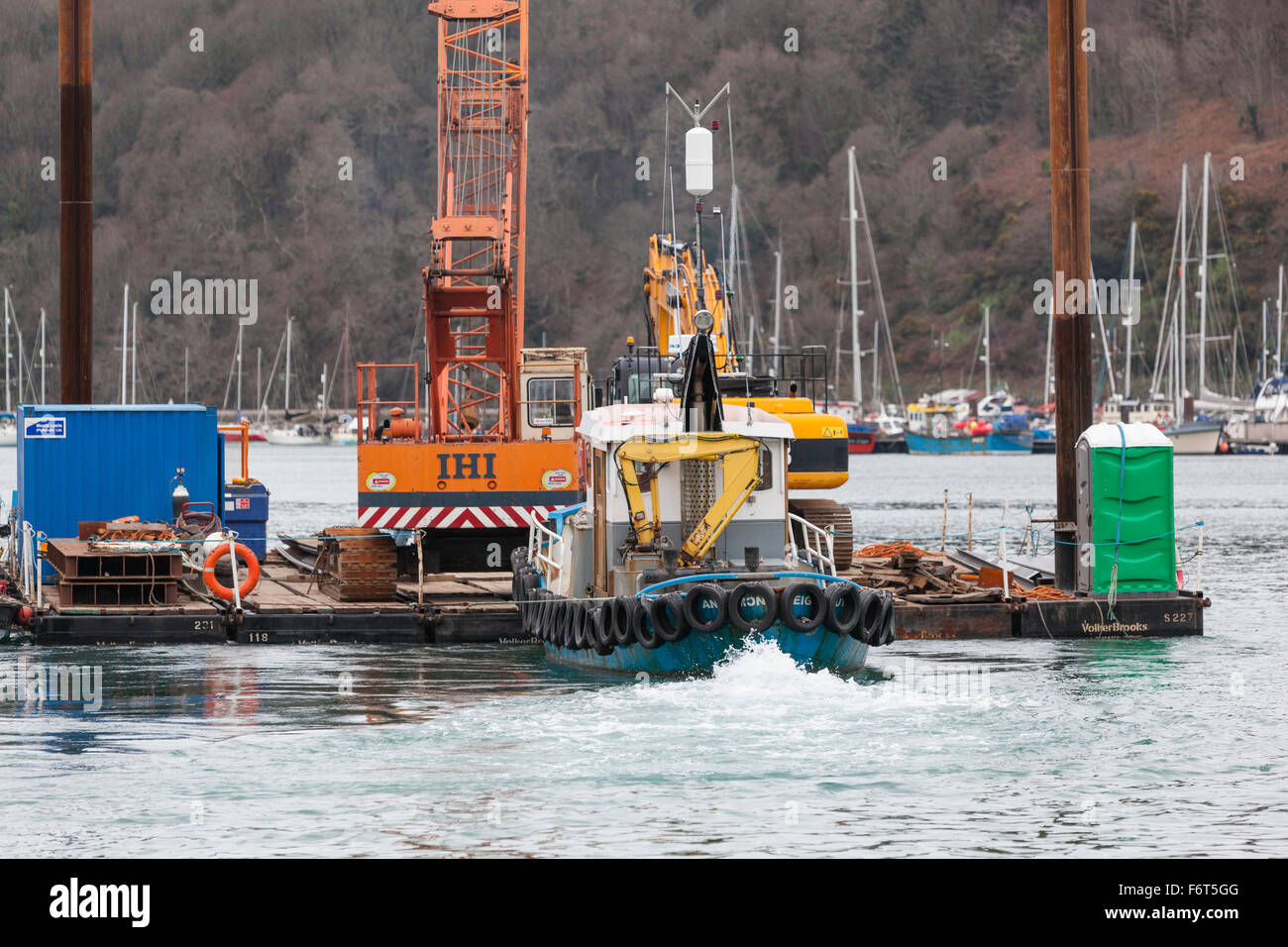A floating construction platform with crane and excavator is pushed ...