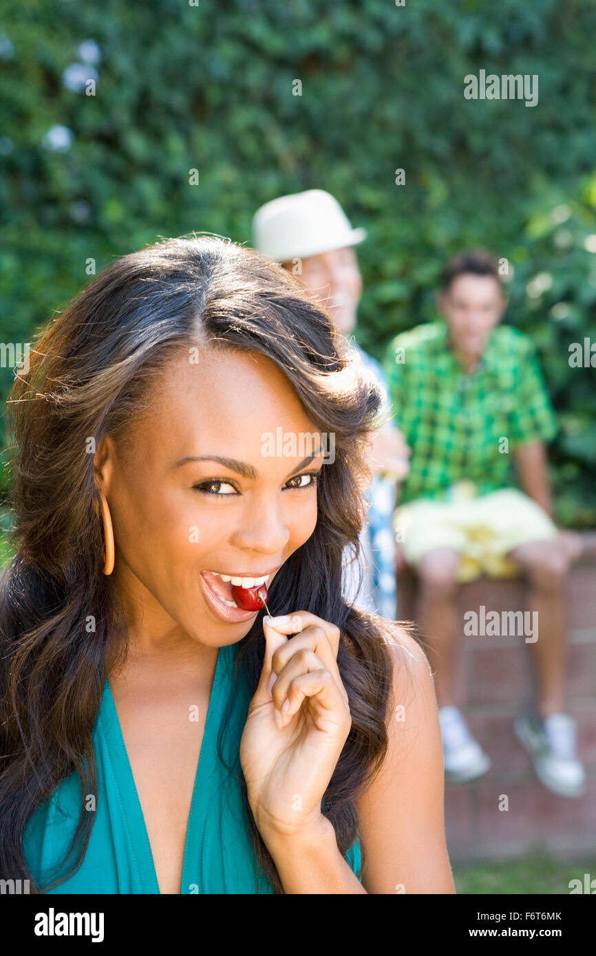 Smiling woman eating cherry in backyard Stock Photo - Alamy