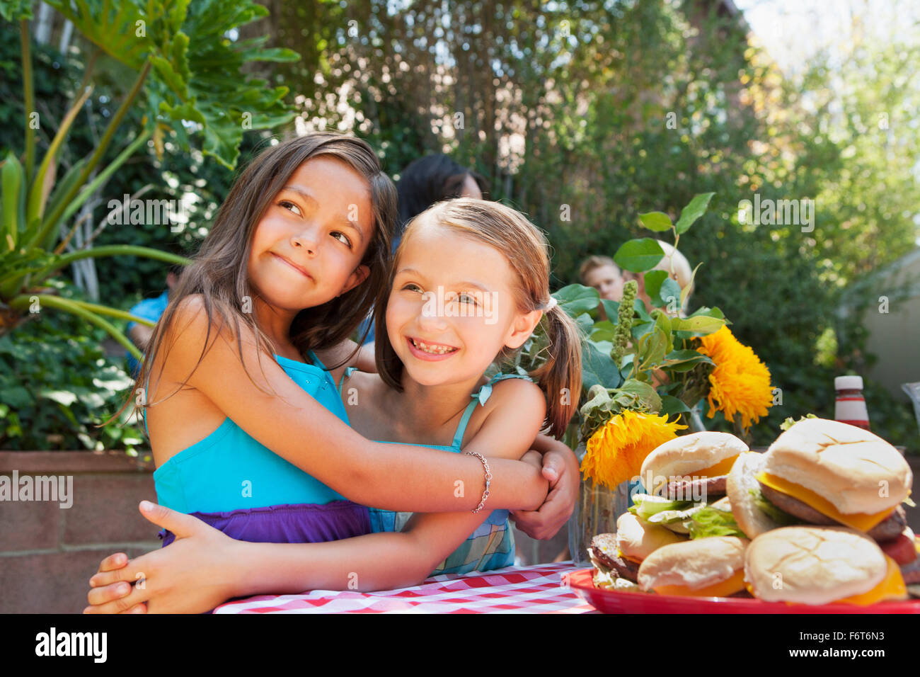Girls hugging at backyard barbecue Stock Photo - Alamy
