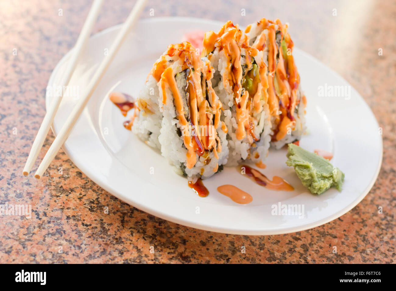 Fancy California sushi roll topped with sushi sauce and spicy ...